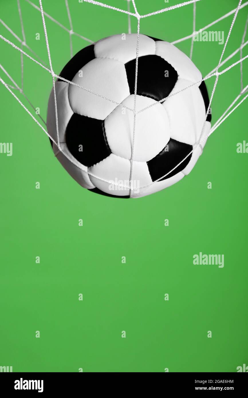 Soccer ball in the net on green background Stock Photo - Alamy