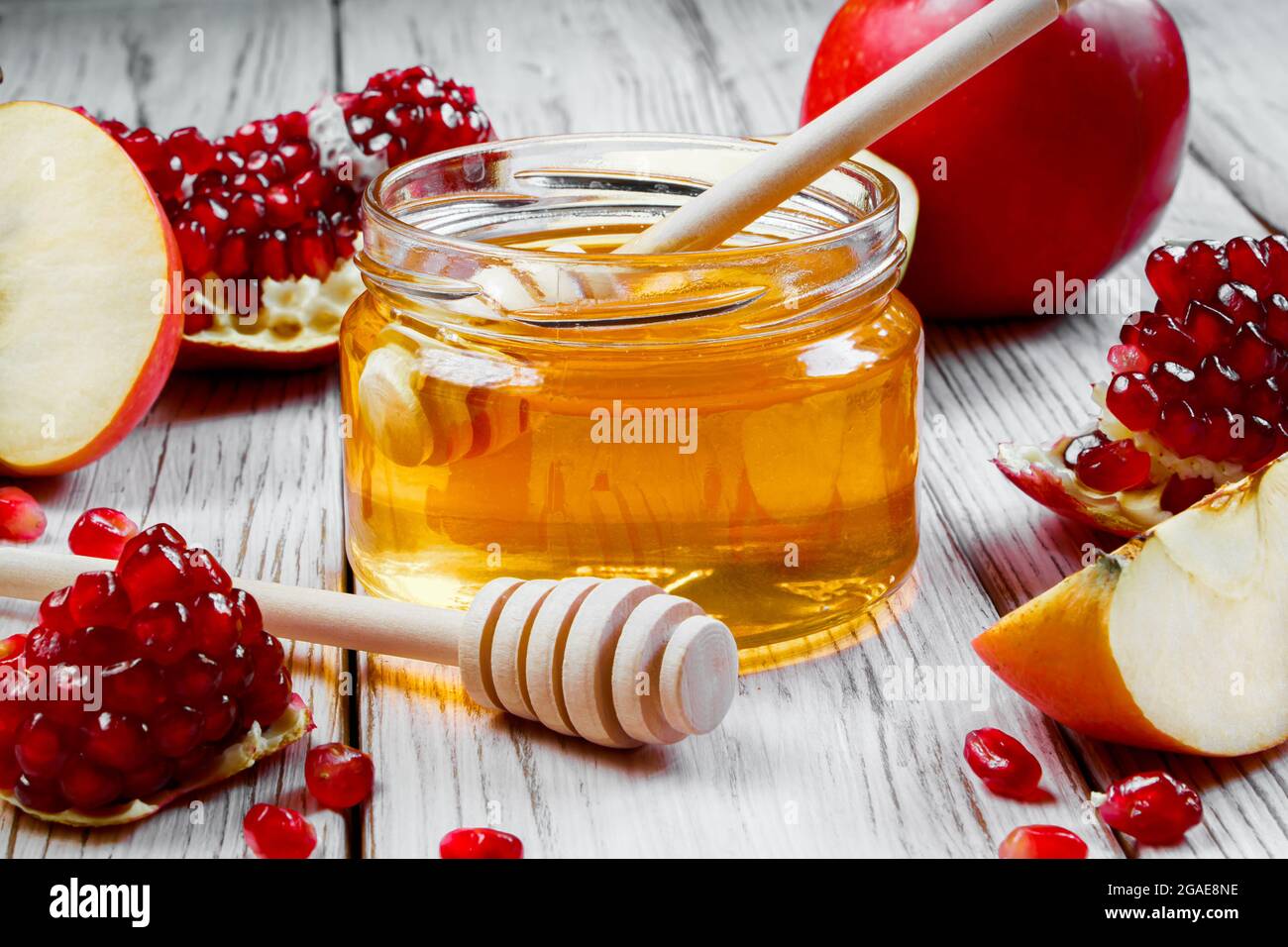 Jar with honey, apples and pomegranates on a white wooden background ...