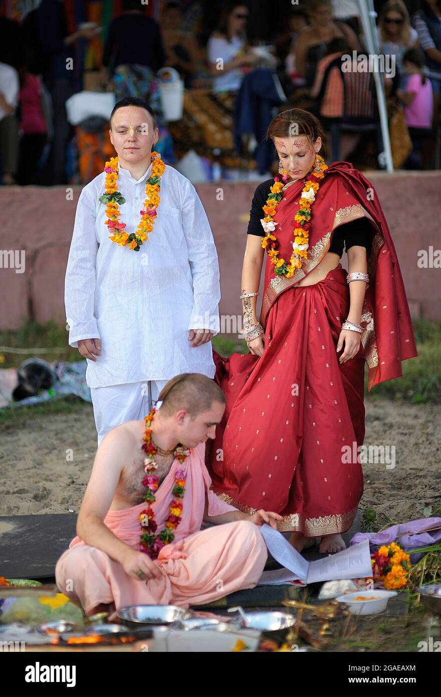 Vedic wedding. Bride and groom standing on the ground monk performing ...