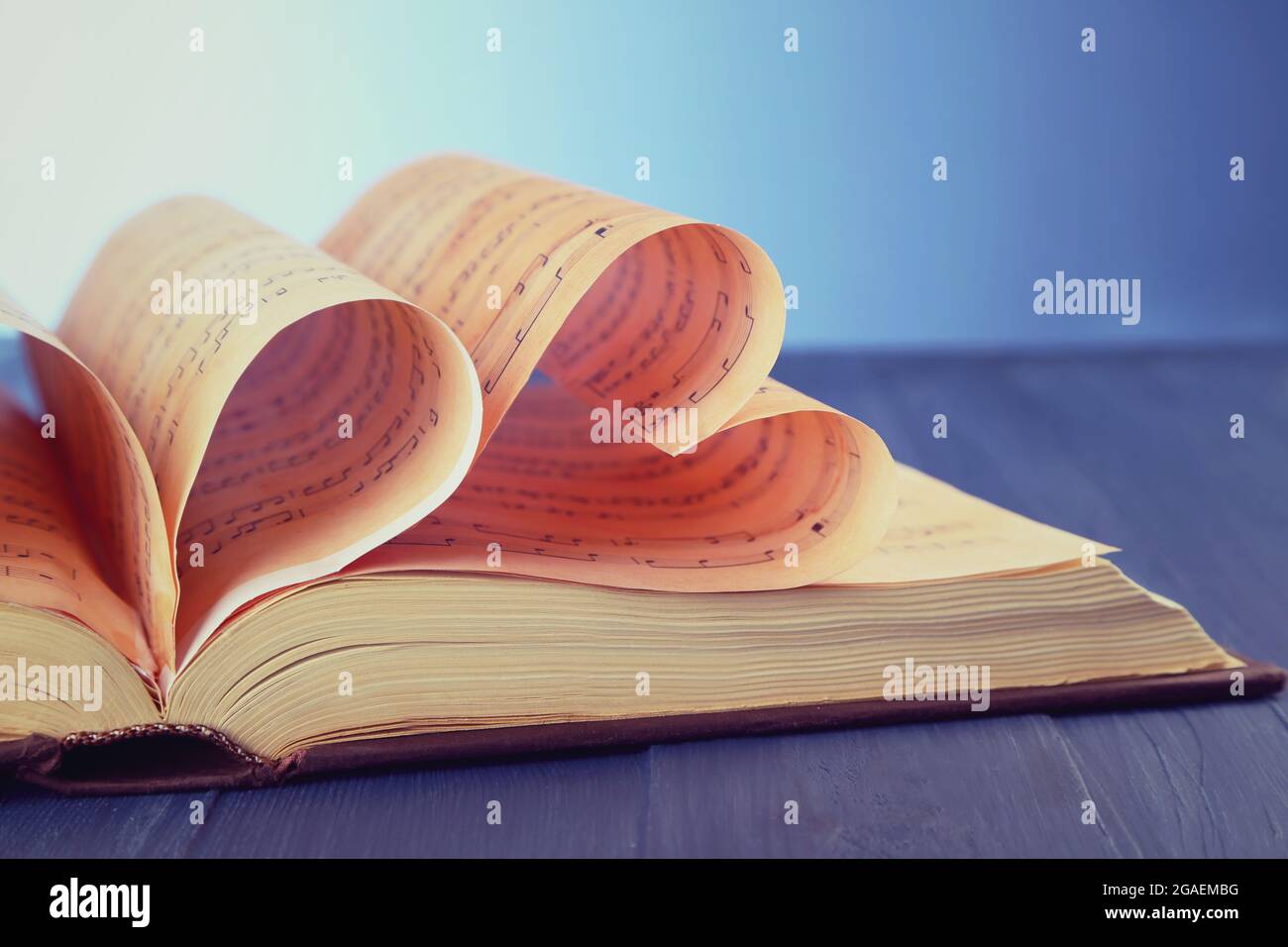 Book pages curved into hearts shapes on blue background Stock Photo - Alamy