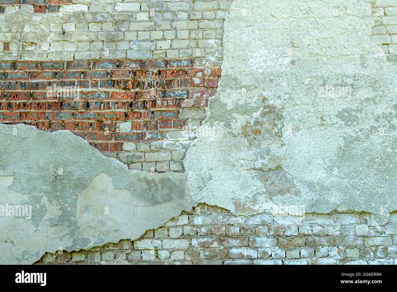 Gray plastered old brickwall with chipped stucco pieces. Grunge red and ...
