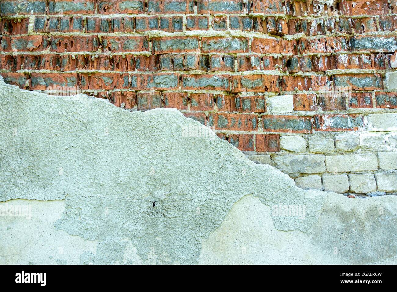 Gray plastered old brickwall with chipped stucco pieces. Grunge red and ...