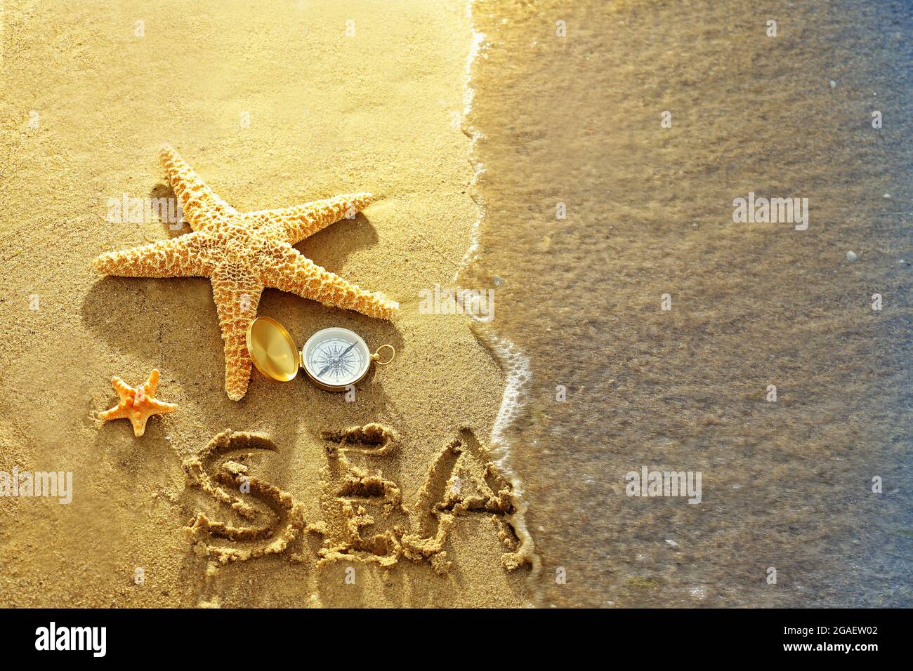 Compass with sea stars on sand beach background Stock Photo - Alamy