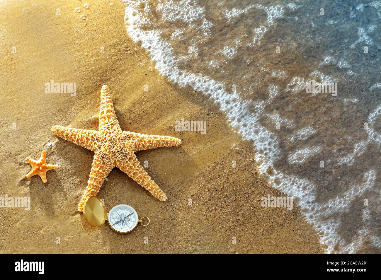Compass with sea stars on sand beach background Stock Photo - Alamy