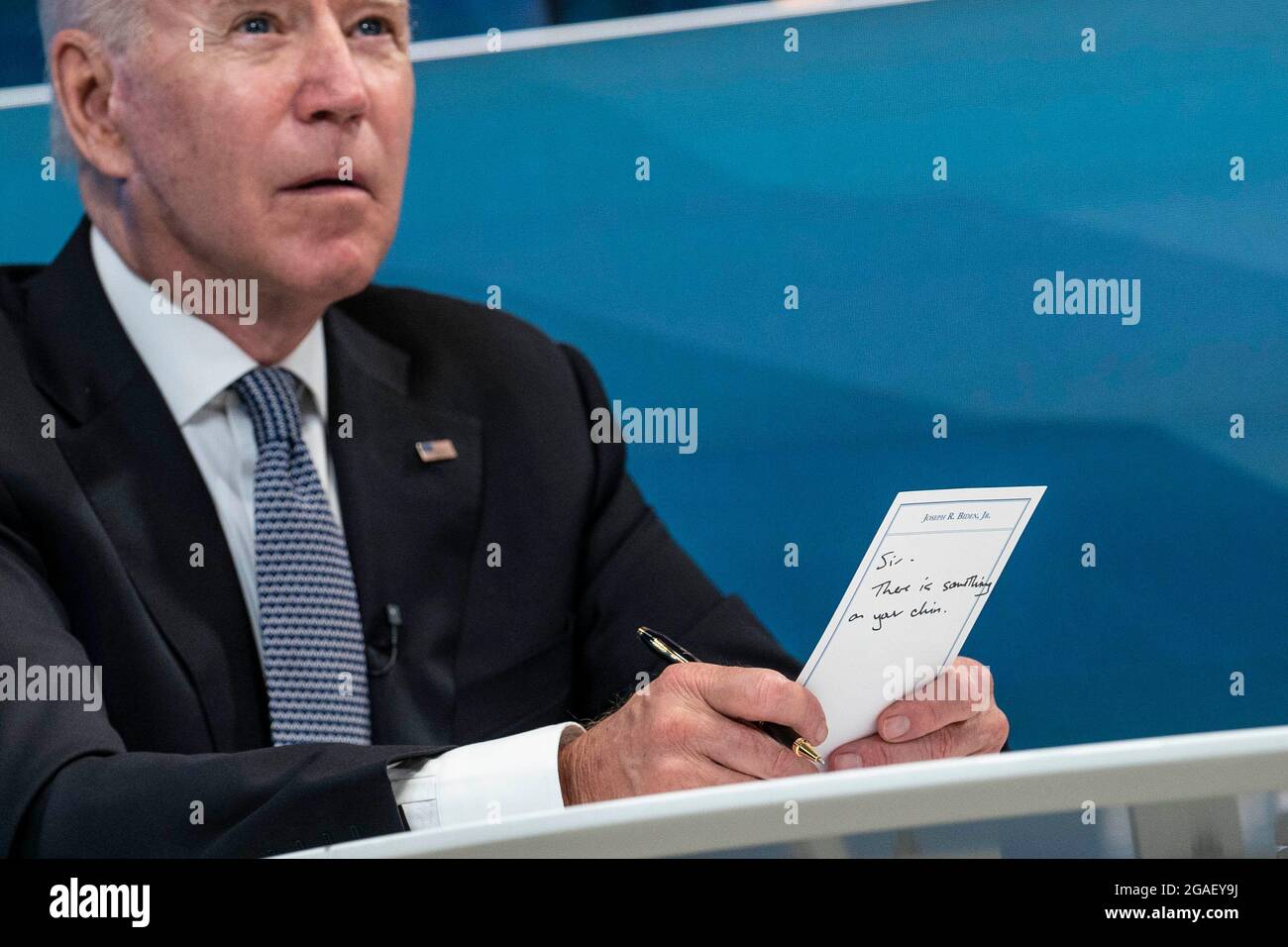 President Joe Biden holds a note from a staff member during a virtual ...