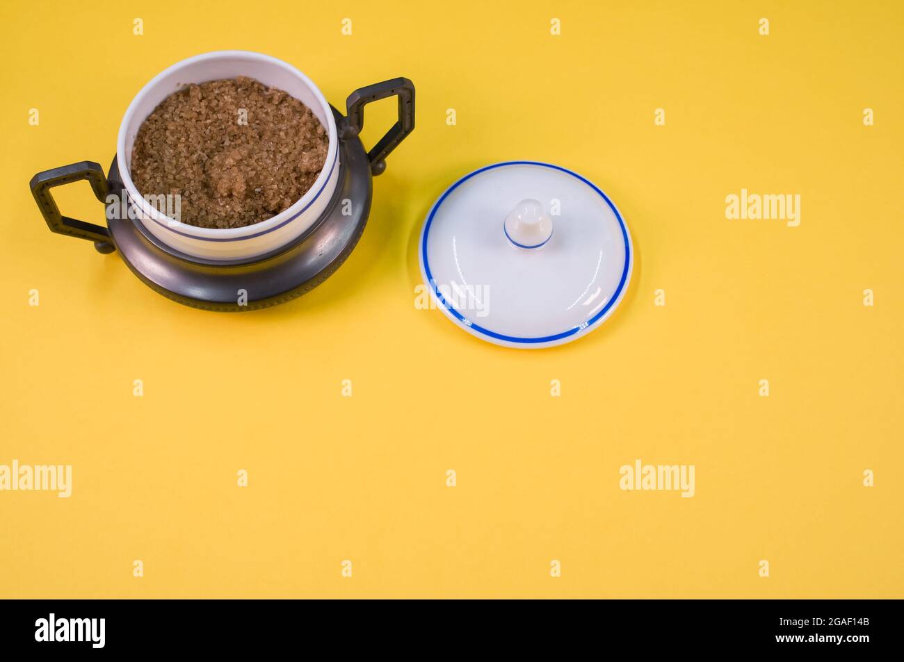 Closeup of brown sugar in a small ceramic jar on a yellow table Stock ...