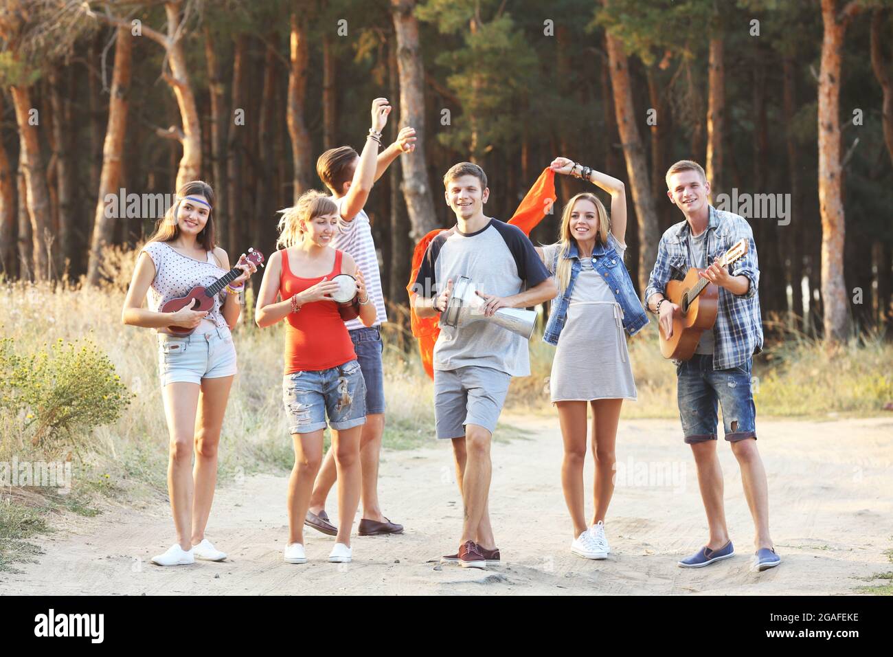 Happy smiling friends playing musical instruments in the forest ...