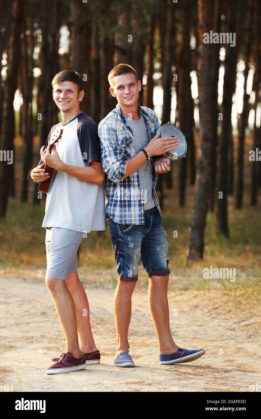 Two handsome guys with musical instruments in the forest outdoors Stock ...