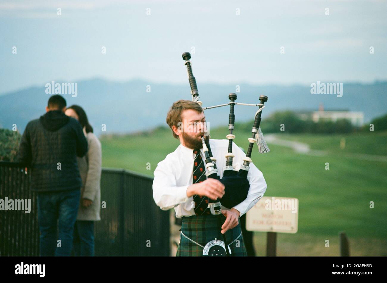 Bagpiper in classic Scottish kilt and costume playing at sunset at the ...