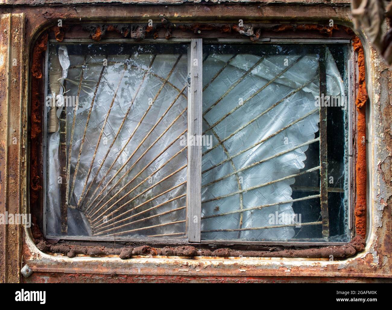 The window of an old rusty wagon, a trailer, with an iron grill and a ...