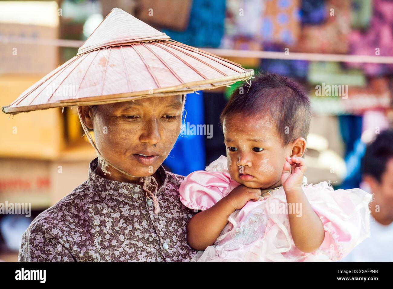 Dark skinned Burmese mother wearing thanaka face powder and conical hat ...