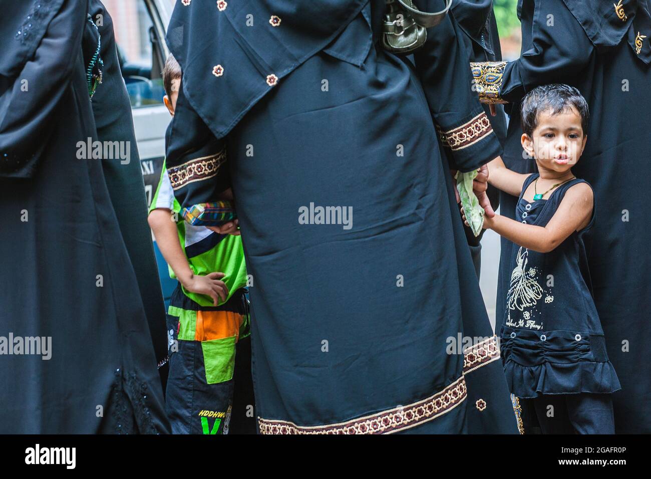 Young Muslim girl peeking out from behind taller females concealed in ...