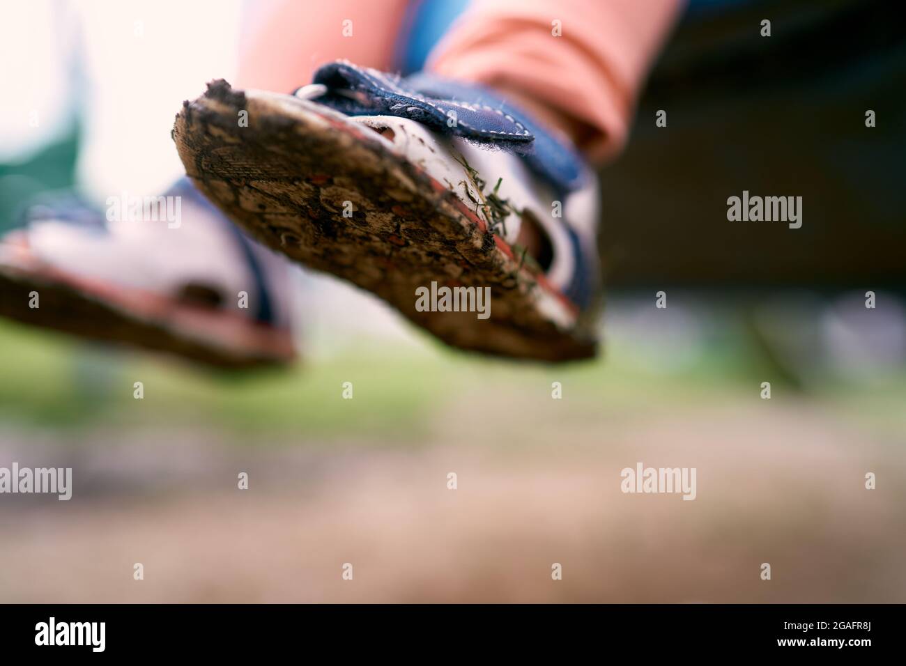 Mud-stained sandals on the feet of a child. Close-up Stock Photo - Alamy