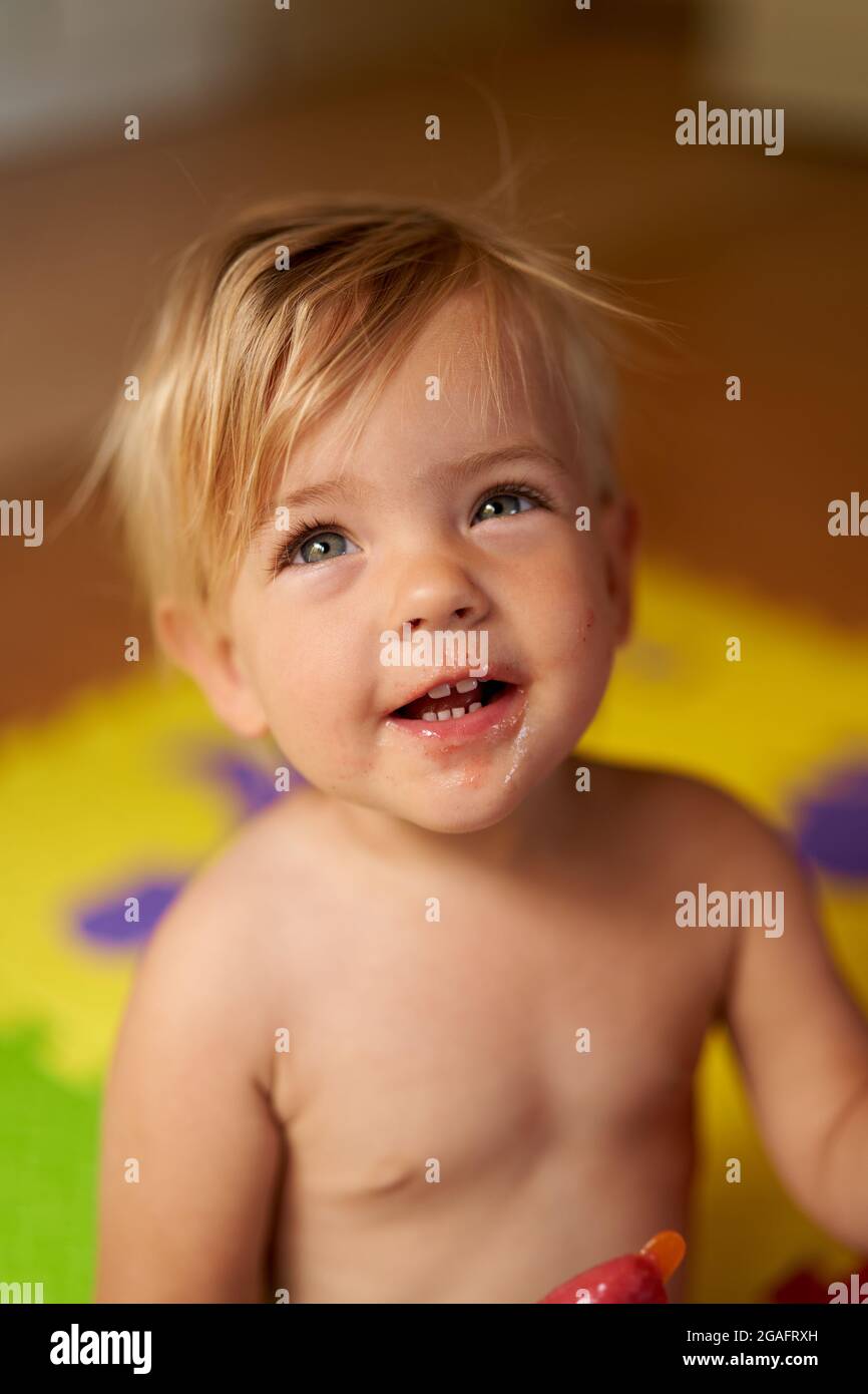 Laughing little kid with dirty face and ice cream in hand sits on the ...