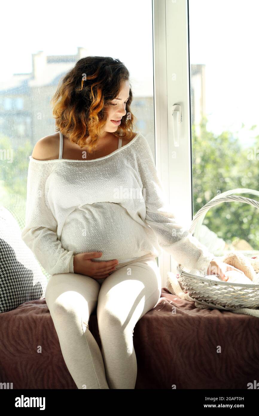 Pregnant woman sitting on window board in the room Stock Photo - Alamy