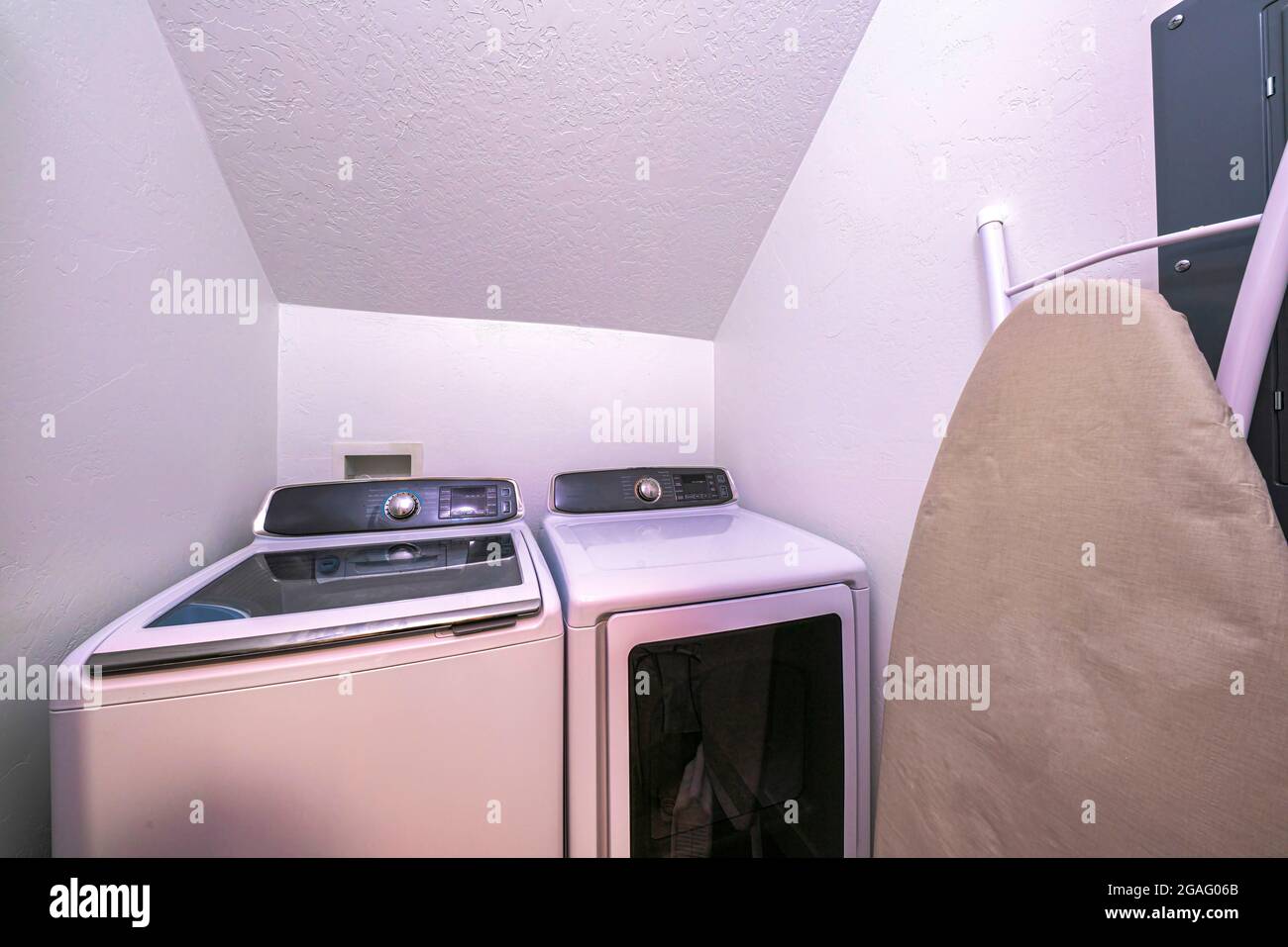Small tight laundry room with slope ceiling and laundry appliances ...
