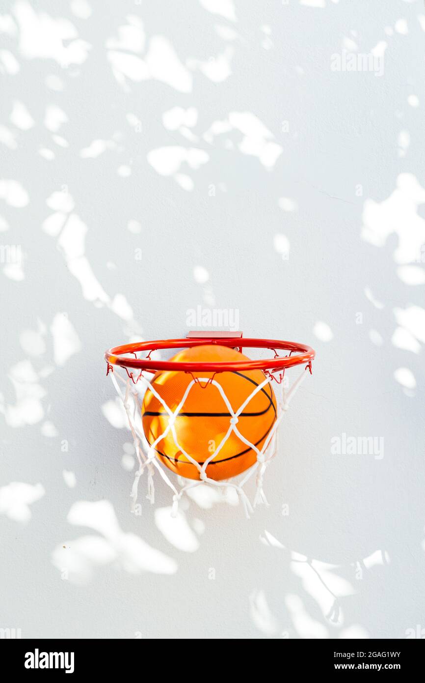 Basketball ring on a white wall. The ball falling through the hoop ...