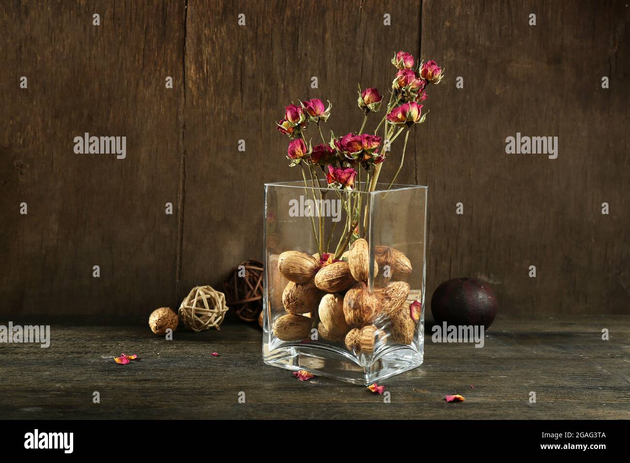 Composition of nuts, wooden balls and stale flowers in glass on wooden ...