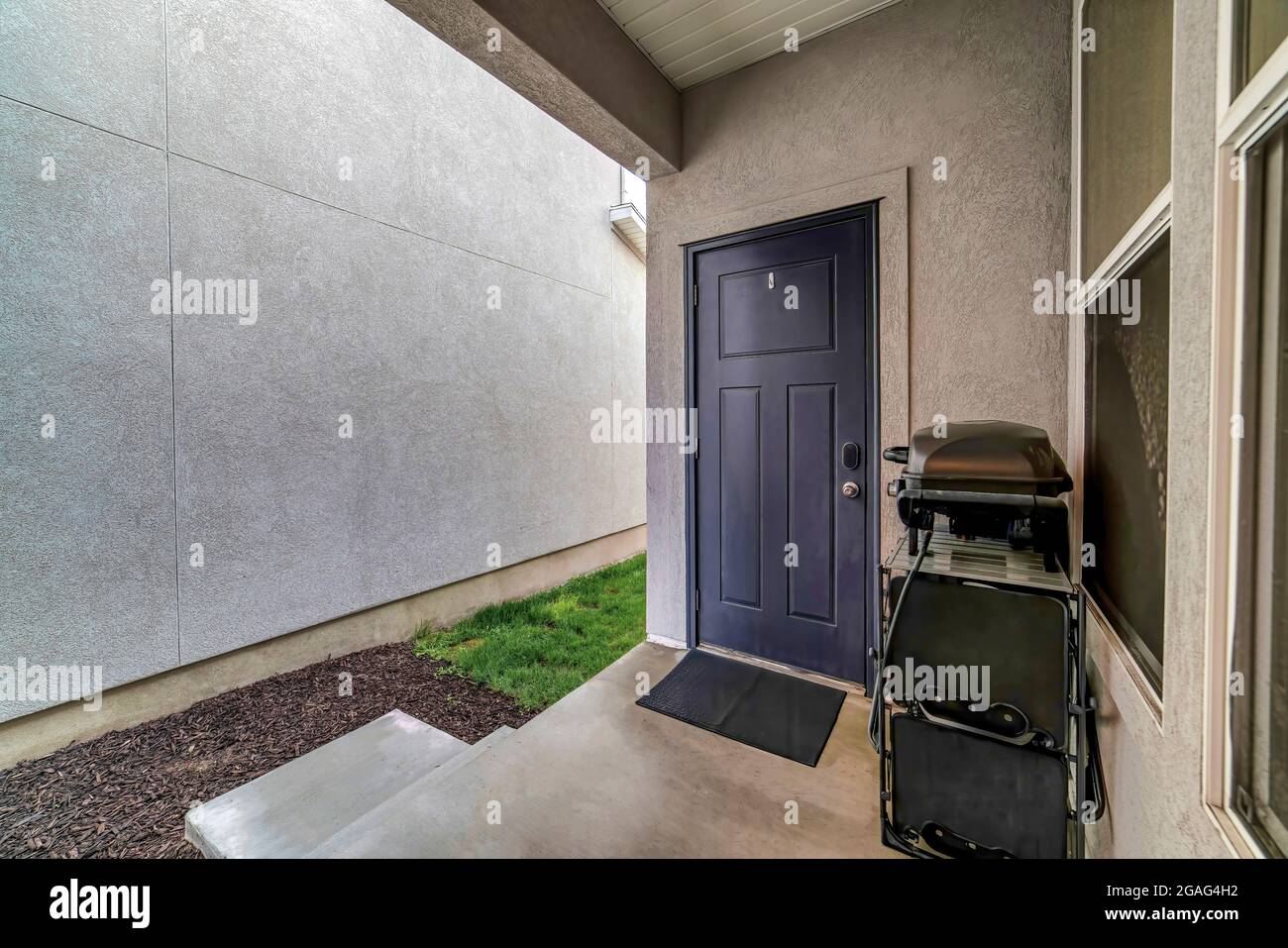 Front door exterior with gas barbecue grill outside beside the windows ...
