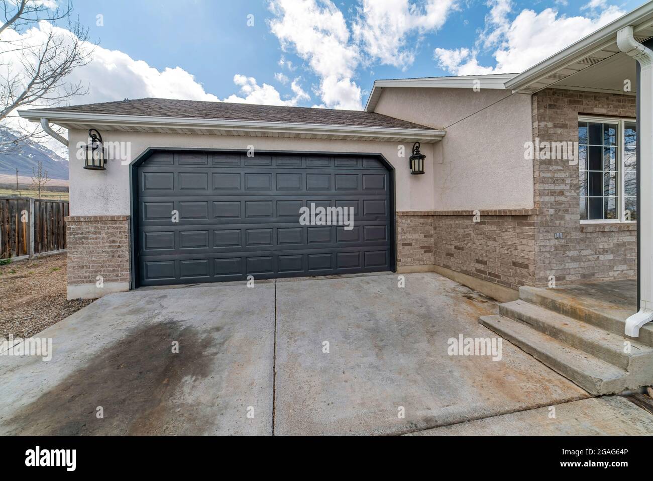 Clipped corner black sectional garage door exterior with a concrete ...