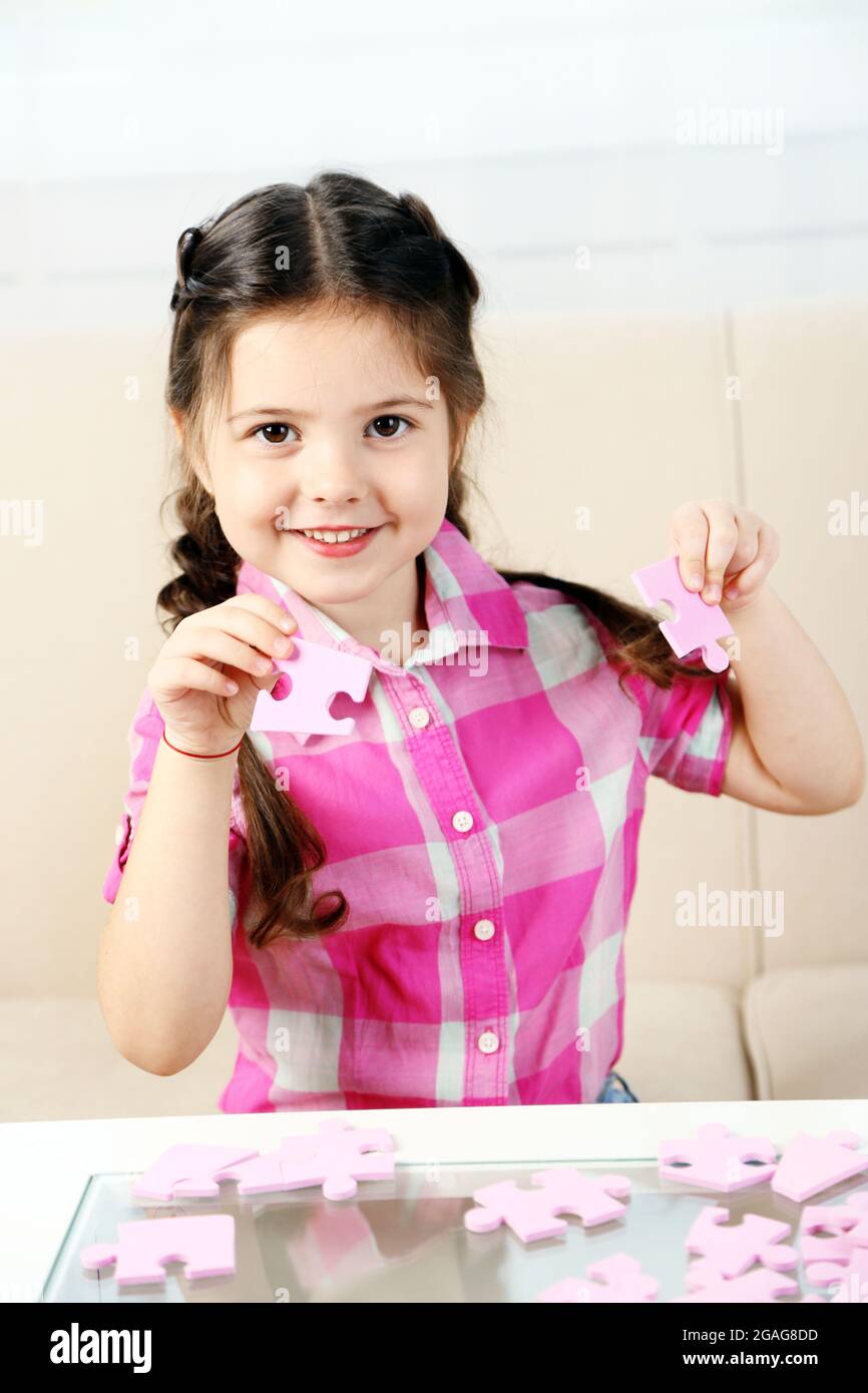 Cute little girl playing with puzzles on home interior background Stock ...