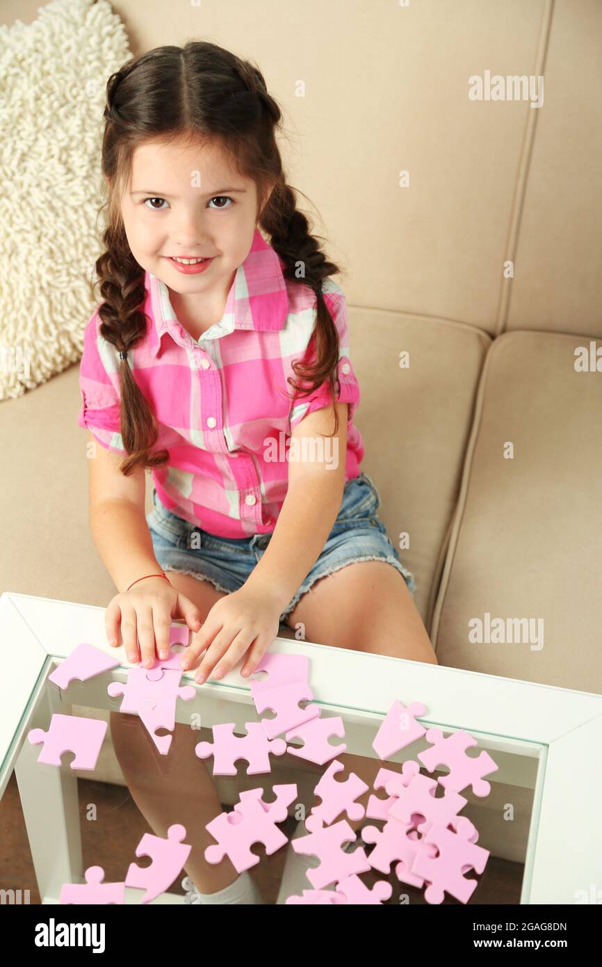 Cute little girl playing with puzzles on home interior background Stock ...