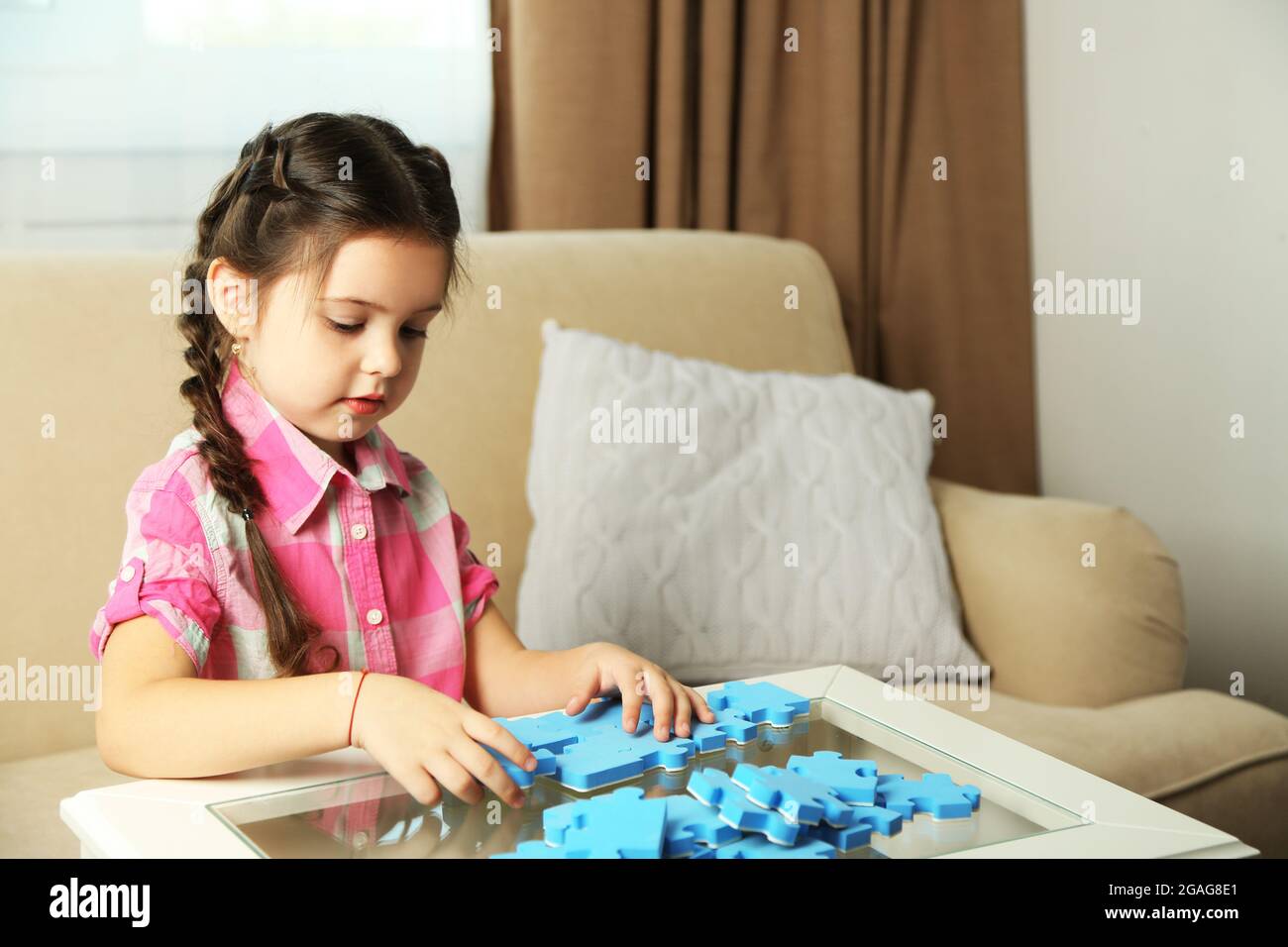 Cute little girl playing with puzzles on home interior background Stock ...