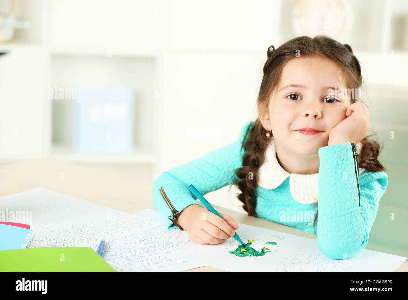 Cute little girl doing her homework, close-up, on home interior ...
