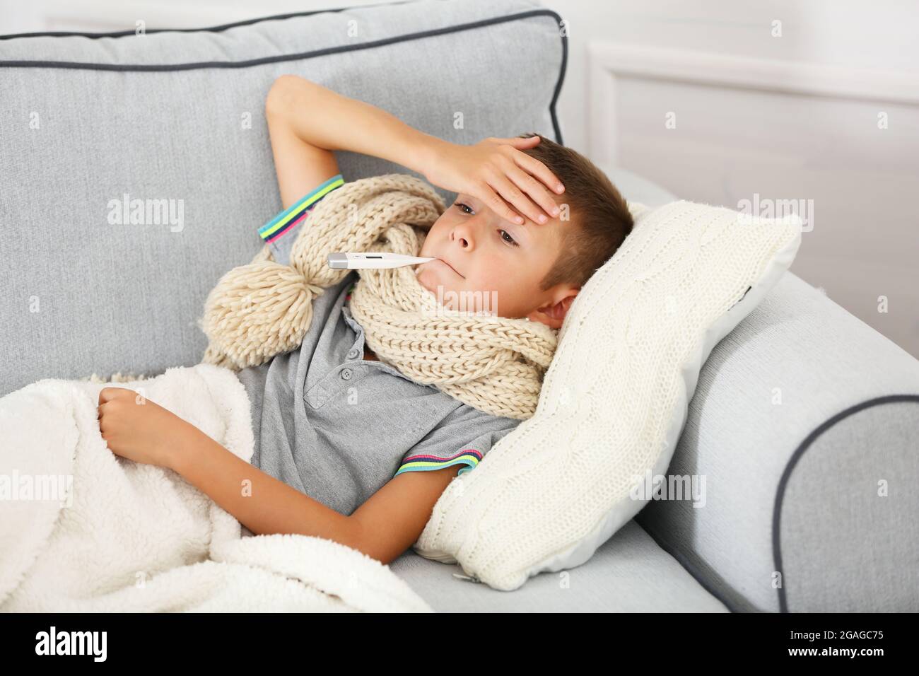Sick boy with cold sitting on sofa Stock Photo - Alamy