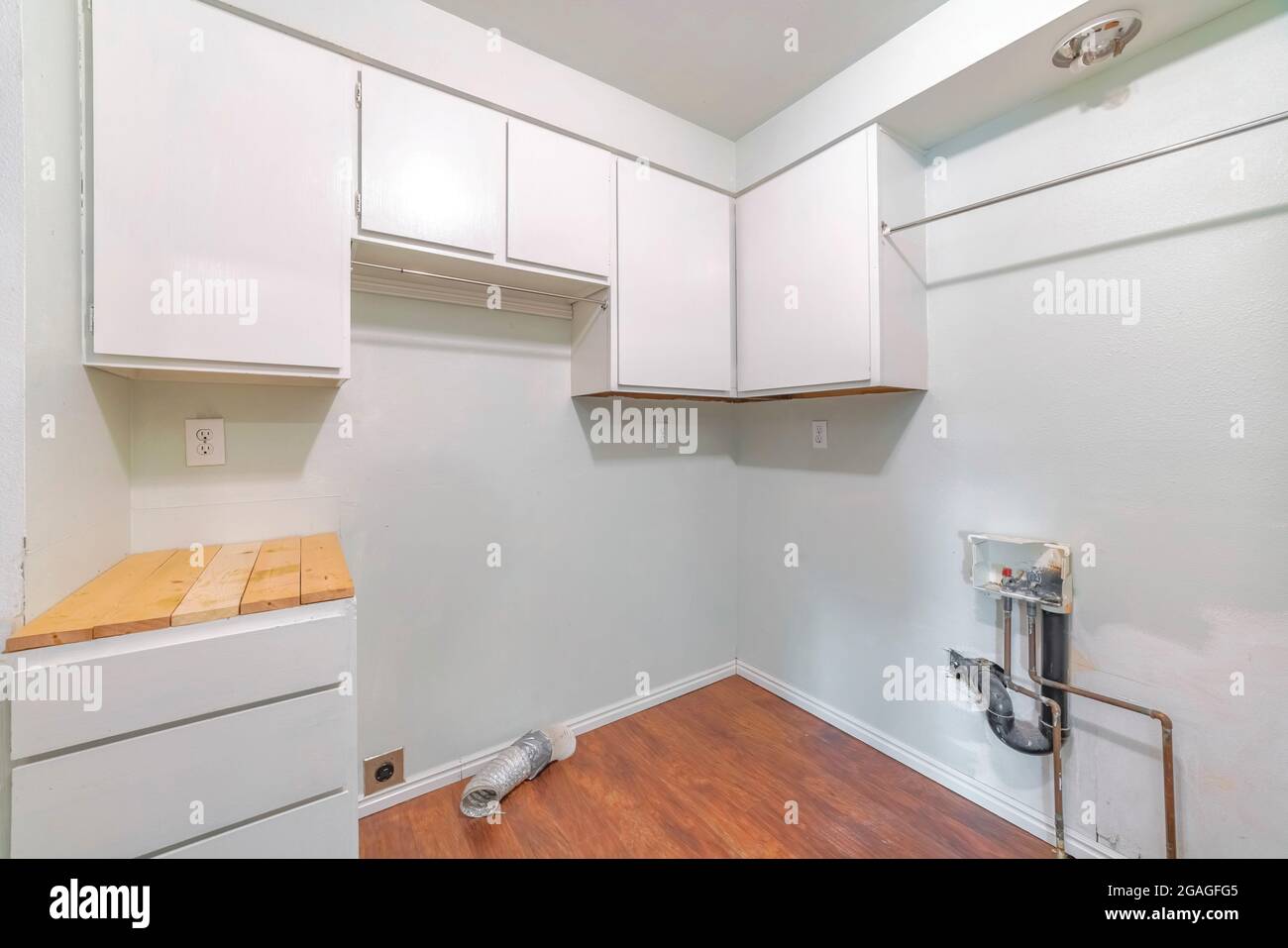 Empty laundry room interior with white wall cabinets and metal rods ...