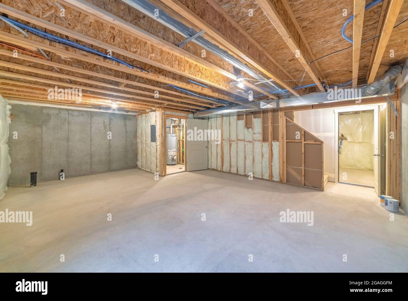 Empty unfinished large basement with concrete flooring and wooden ...