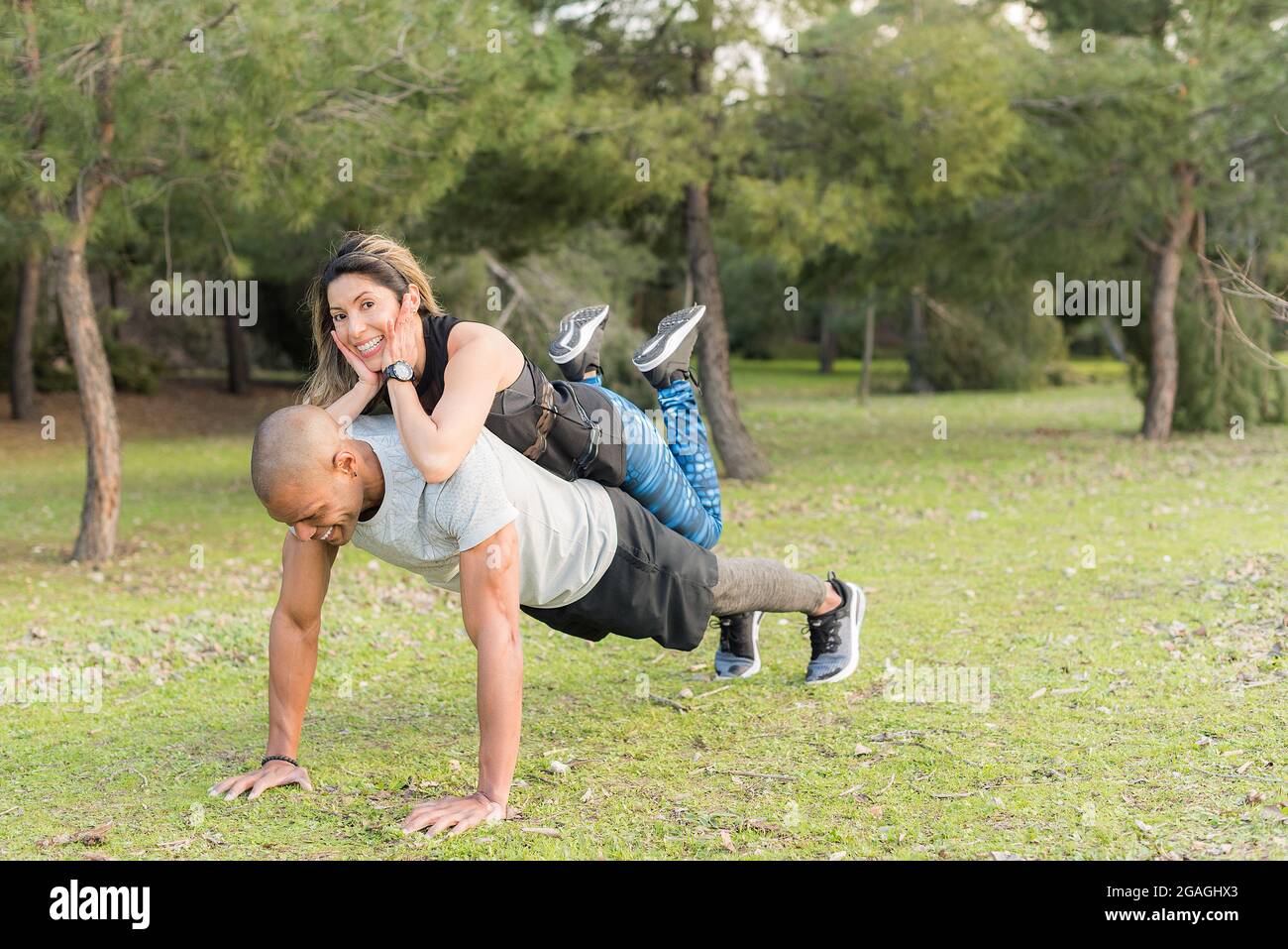 Fitness couple doing push-ups in the park. Woman on back of man Stock ...