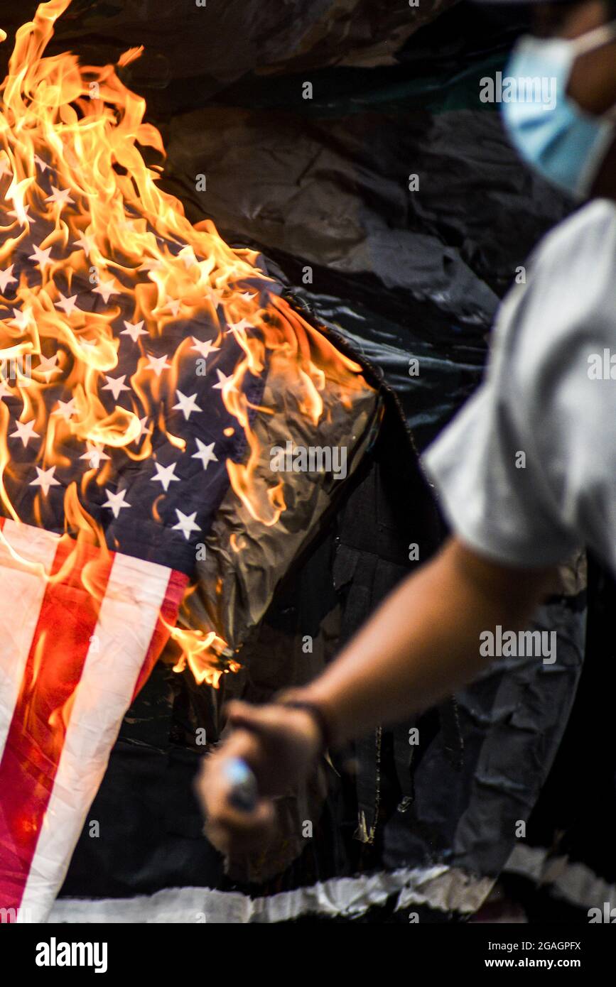 A demonstrator sets fire to a United States flag hanging on a paper ...