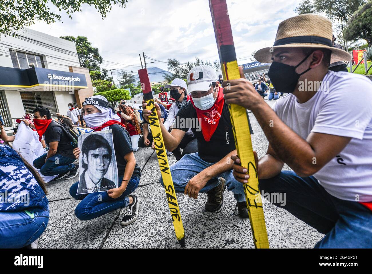 Student demonstrators squat while holding portraits and wood pieces ...
