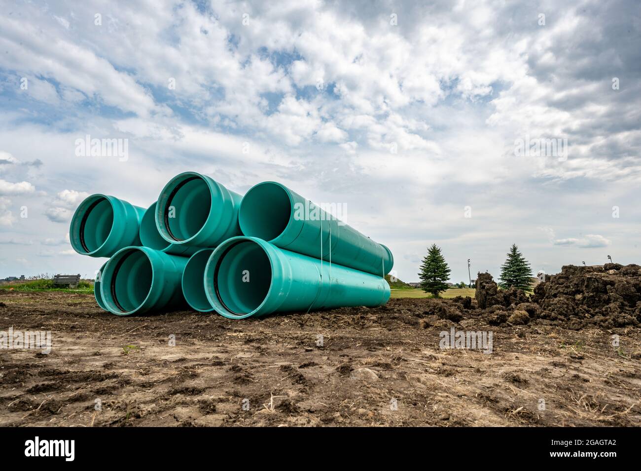 Stacked water main pipe with bell fitting next to an exposed trench for ...