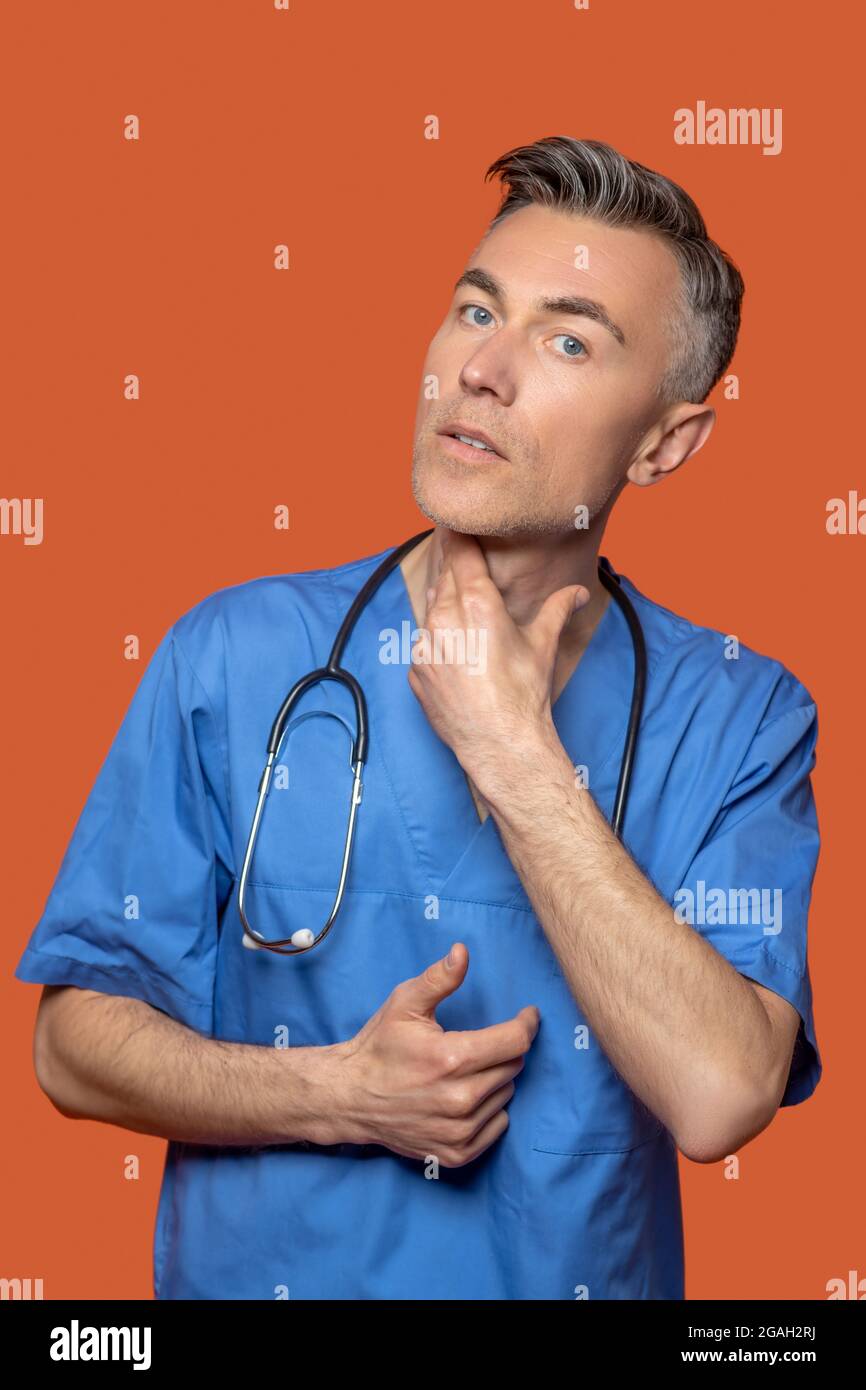 Attentive male doctor touching his neck Stock Photo - Alamy
