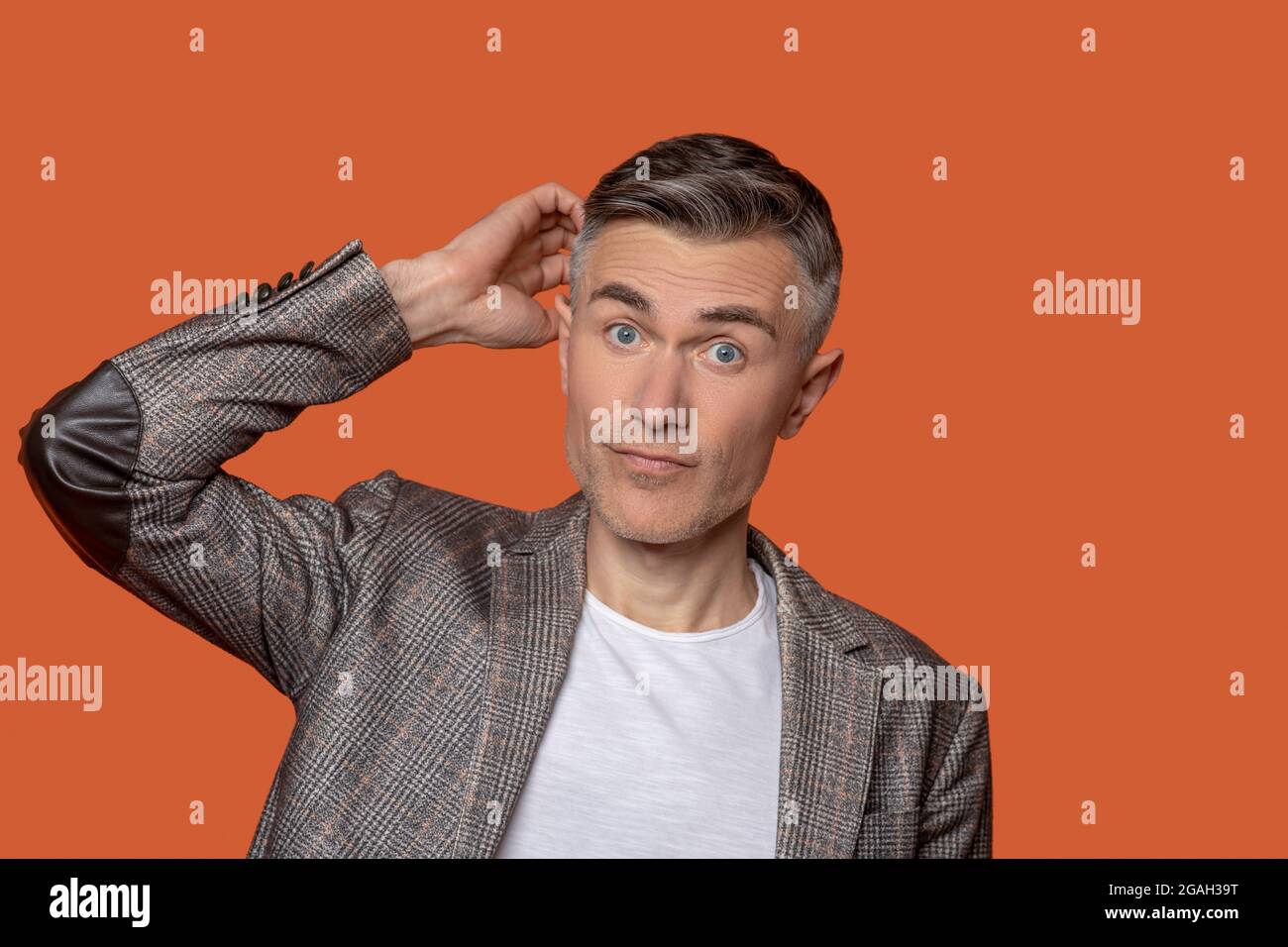 Kind man touching head in good mood Stock Photo - Alamy