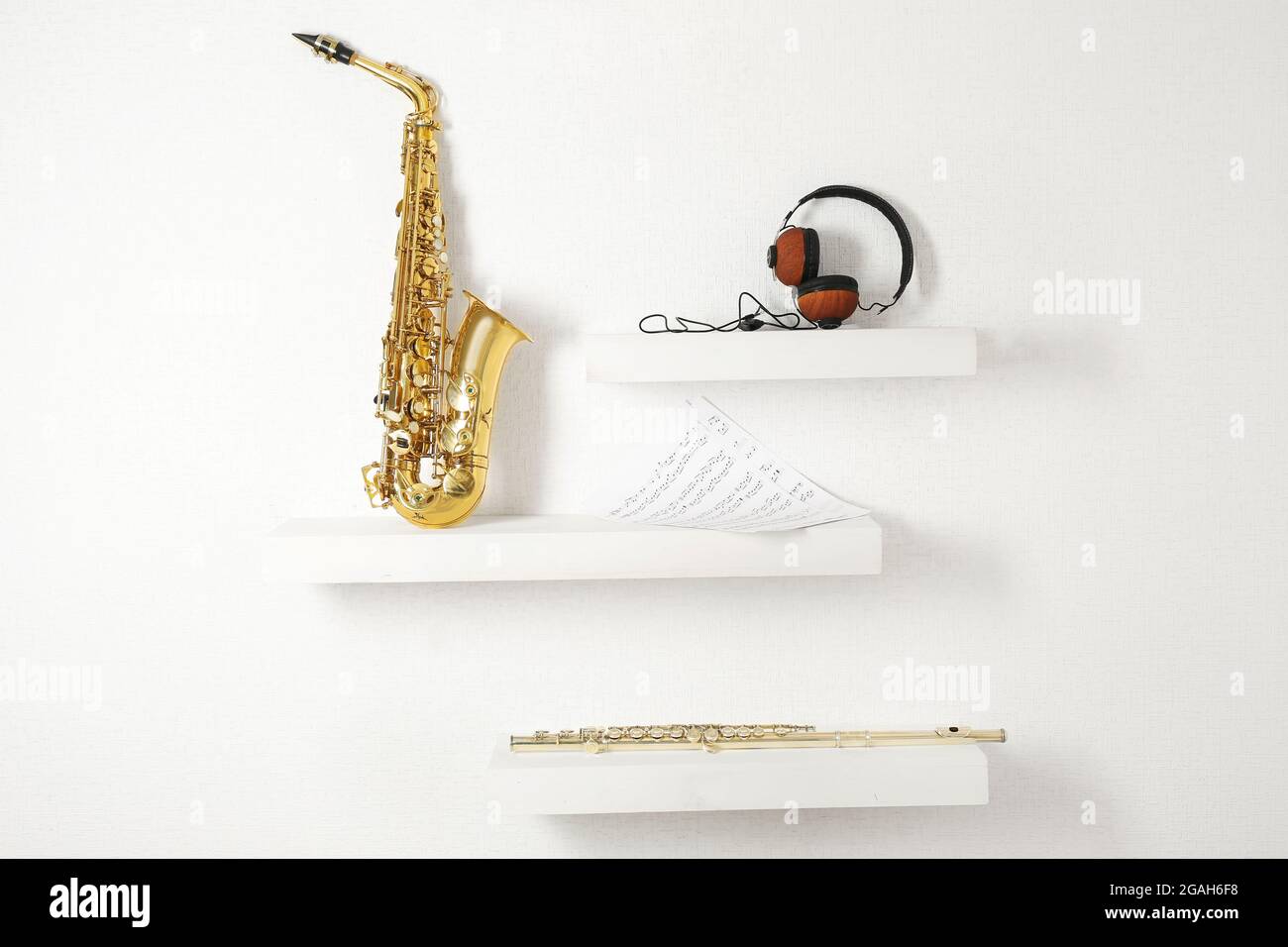 Musical instruments and headphones on decorated shelves against white ...
