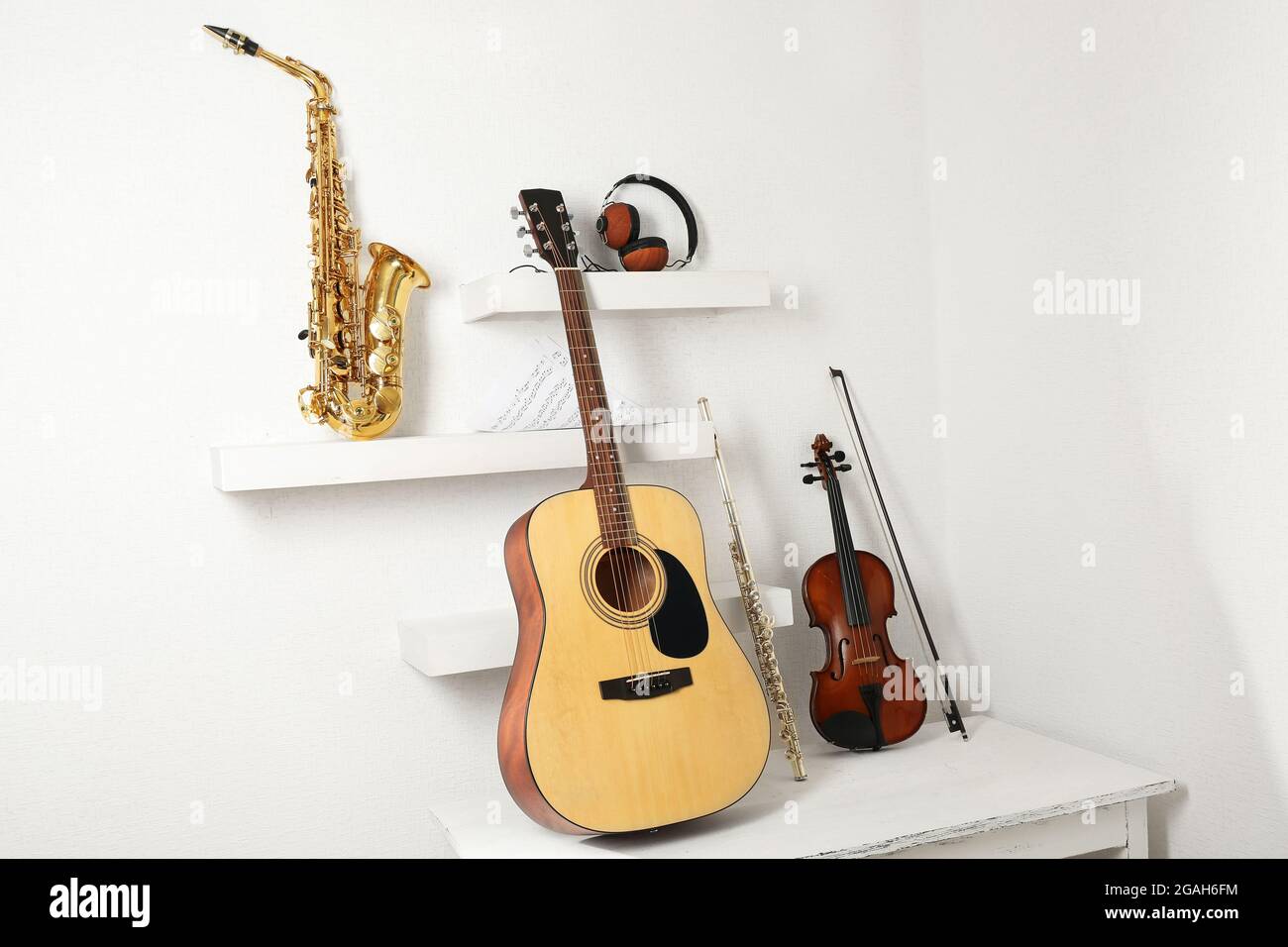 Musical instruments and headphones on decorated shelves against white ...