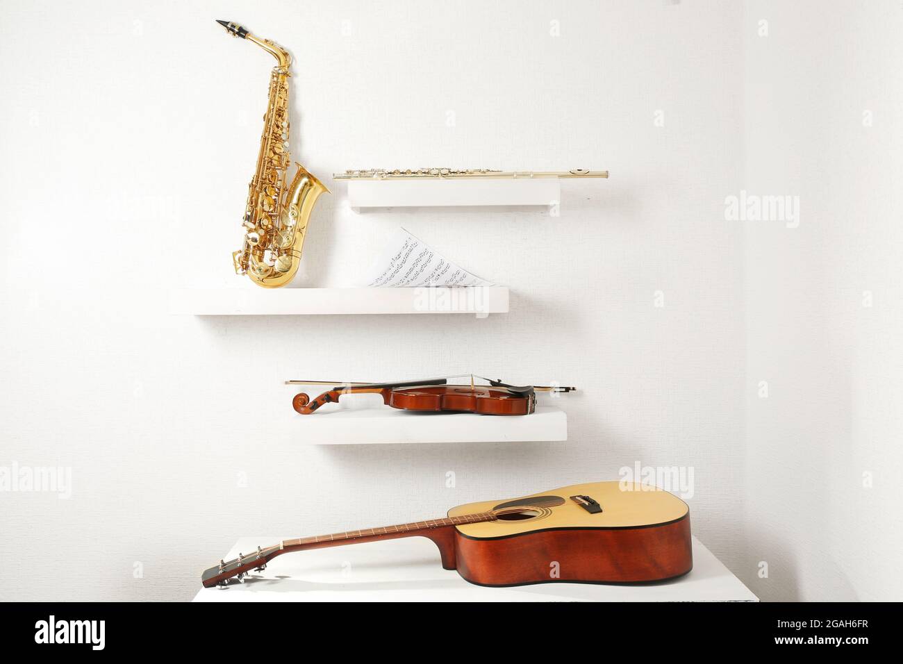 Musical instruments on decorated shelves against white wall background ...