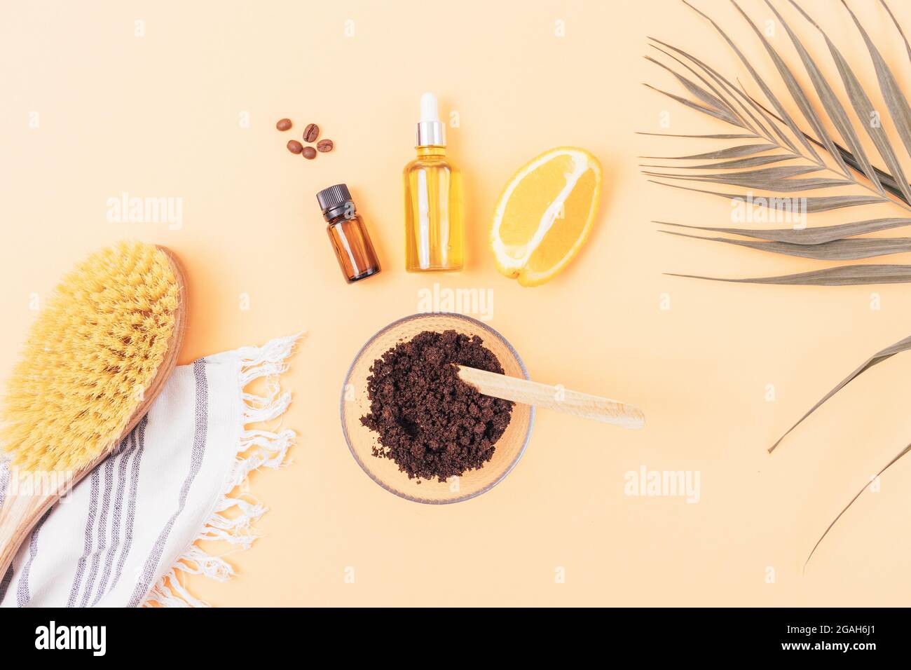 Homemade anti-cellulite scrub with coffee beans and natural oils next to massage brush, bath ...