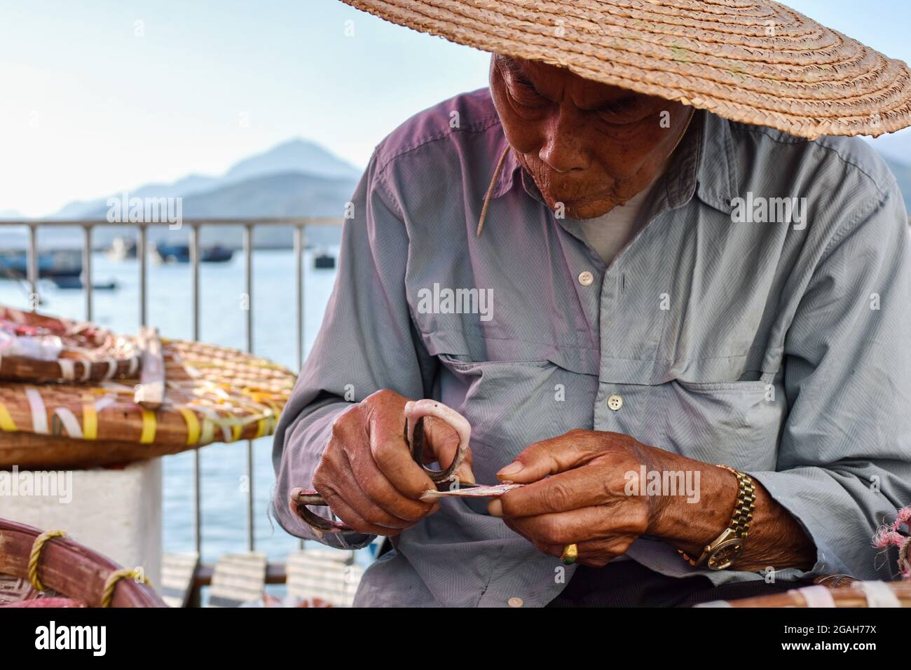 An elderly man seen peeling a dried up fish in Cheung Chau Island Stock ...