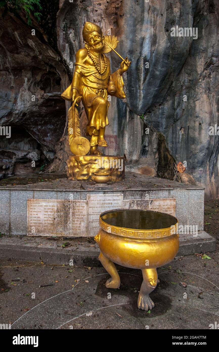 A golden statue of an old man with fan of large leaves and golden vat ...