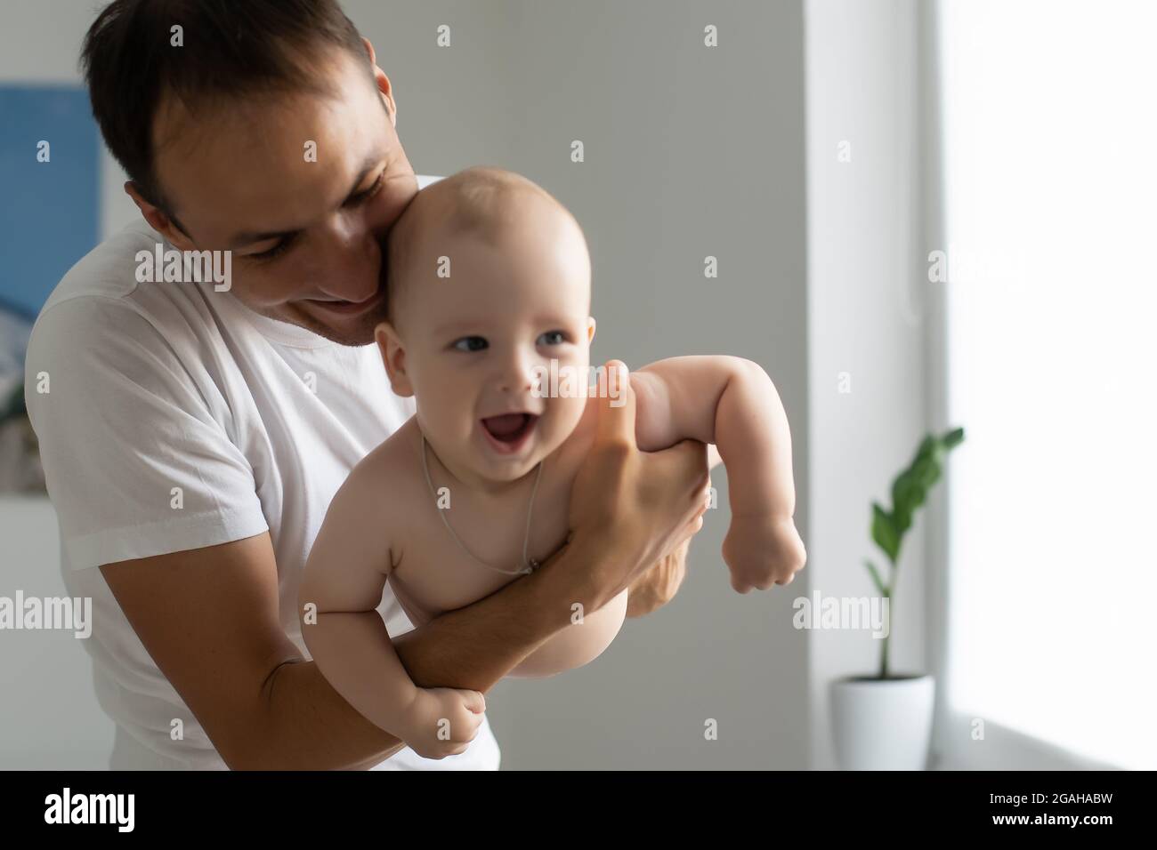 Father Hugging Newborn Baby in white bedroom Stock Photo - Alamy