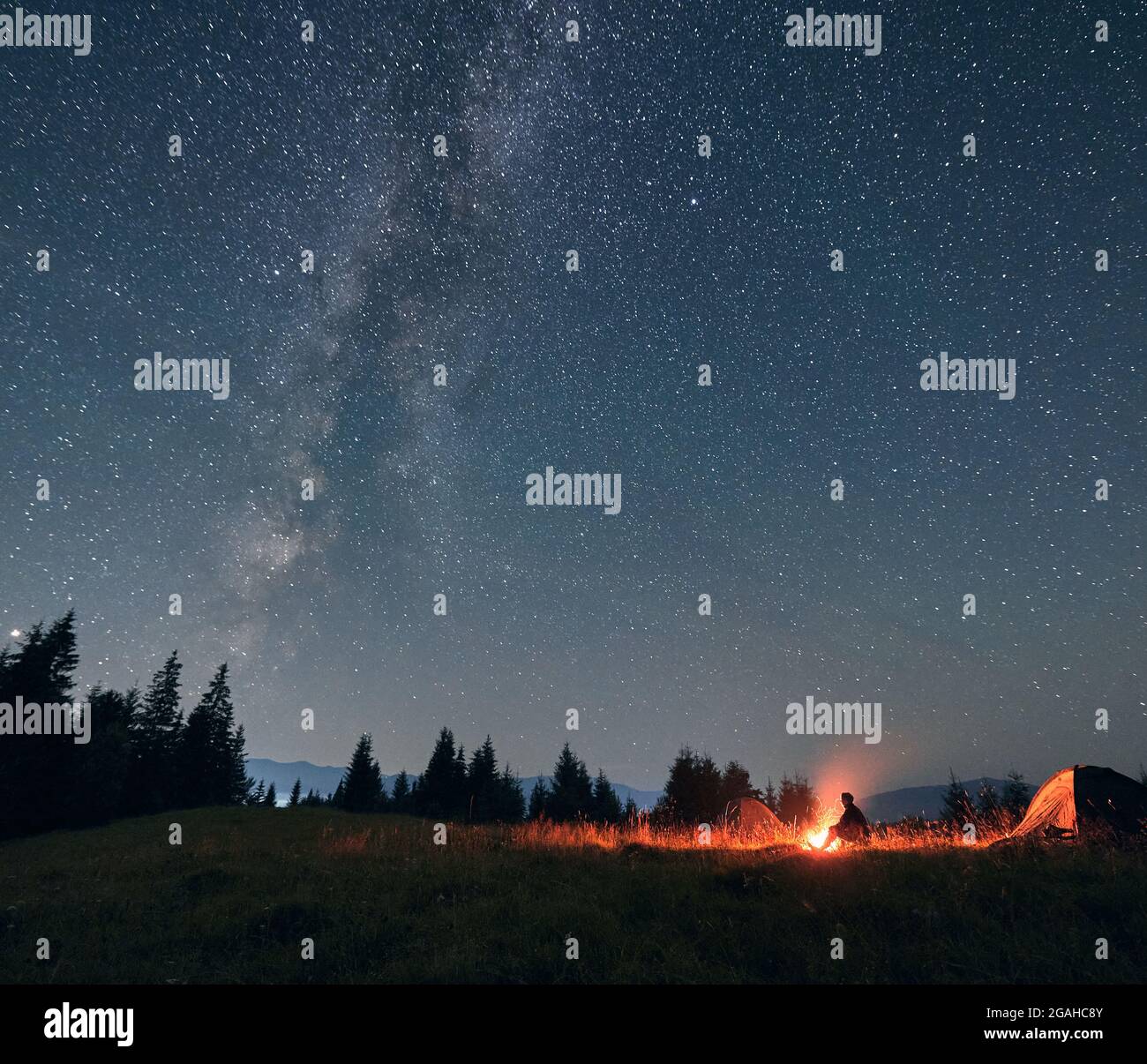 Male traveler looking at beautiful night sky with stars and Milky way ...