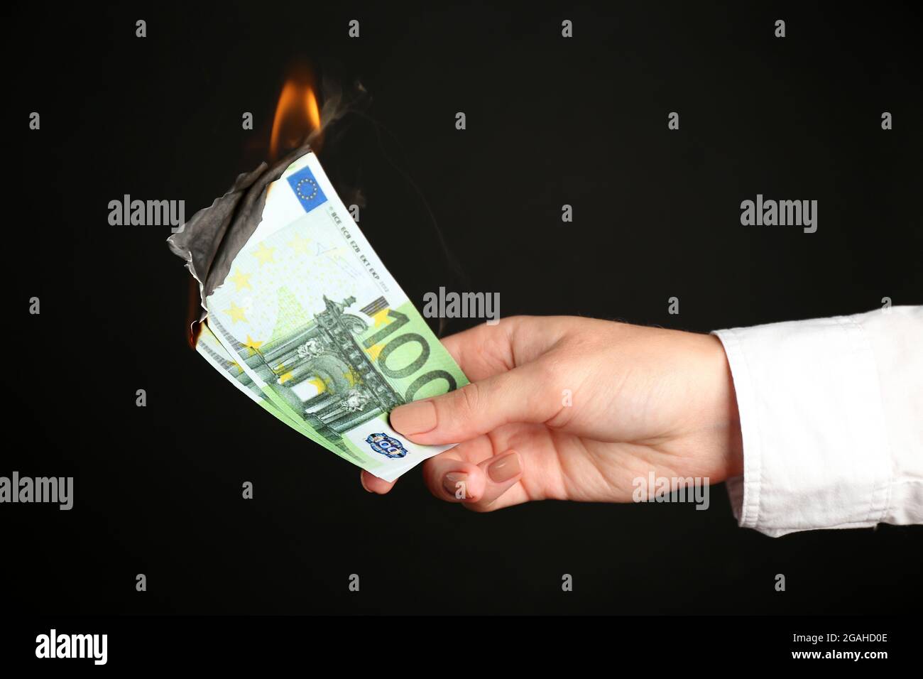 Woman burning Euros banknotes on black background Stock Photo - Alamy