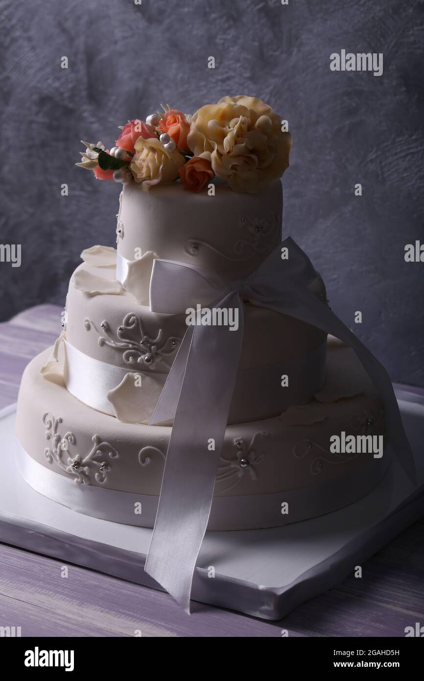 Wedding cake decorated with flowers on grey background Stock Photo - Alamy