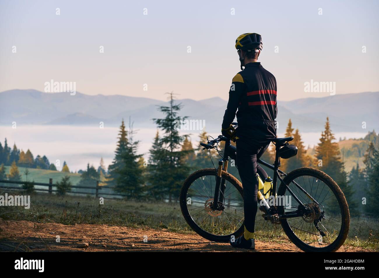 Back view of male cyclist in cycling suit standing with bike in the ...
