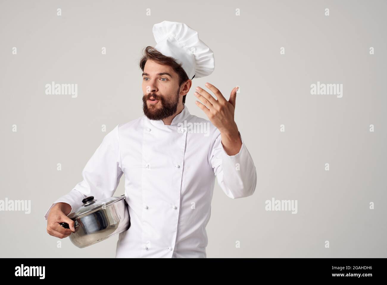 a man in a cook's uniform a pan in his hands trying food work Stock ...