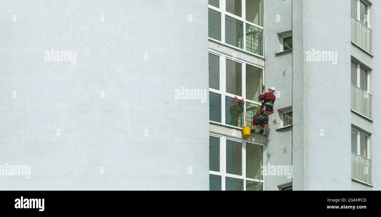 A man washes windows in a multi-storey building. Professional window ...
